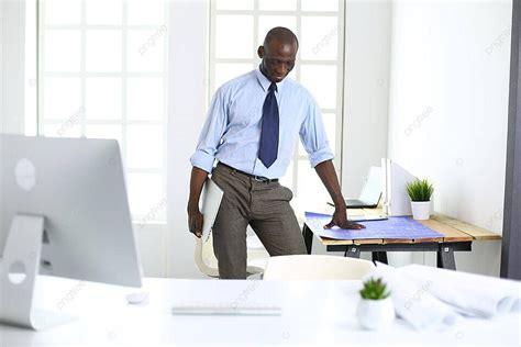 Architect Of African Descent Using Computer And Blueprints In Their