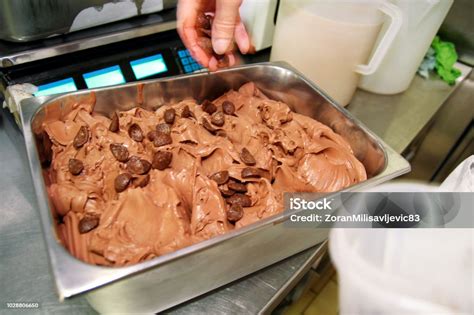 요리사 유니폼 여성 제과 아이스크림 공장에서 일하고 있다 그녀는 어두운 초콜릿 아이스크림 맛과 강철 컨테이너에 추가 초콜릿 위기 비스킷 덩어리의 훈장 이다 제조입니다 강철에