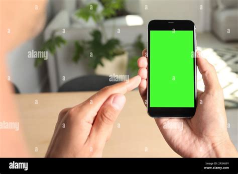 Chroma Key Compositing Man Using Smartphone With Green Screen Indoors Closeup Mockup For