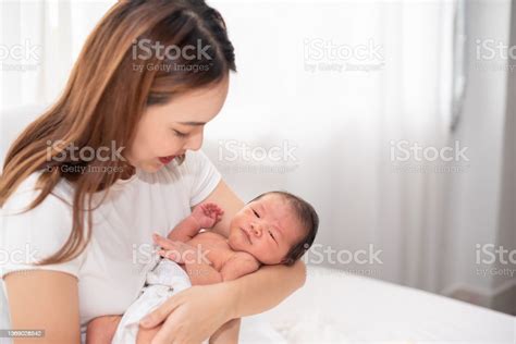 집에서 갓 태어난 아기를 돌보는 아시아인 의 엄마 행복한 엄마는 손에 잠자는 유아 아이를 들고 어머니는 그녀의 작은 한 달 된
