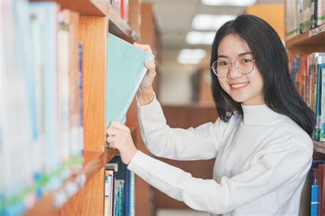 학교 교육 지식 대학 개념으로 돌아가기 도서관 학습 및 교육 개념에 행복하게 서있는 그녀의 책을 들고 있는 아름다운 여성 대학생