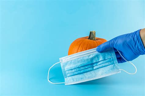 오렌지 호박 근처에서 의료 용 보호 마스크를 들고 있는 파란색 장갑을 끼고 있는 손 10월에 대한 스톡 사진 및 기타 이미지 10월 가을 건강관리와 의술 Istock
