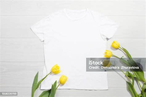흰색 티셔츠 모형 템플릿 빈 셔츠 평면도입니다 흰색 나무 배경입니다 어머니 여성의 날 휴일입니다 노란 튤립 생일 꽃다발 꽃이 있는 여자 티셔츠 봄의 모습 여성 액세서리 0