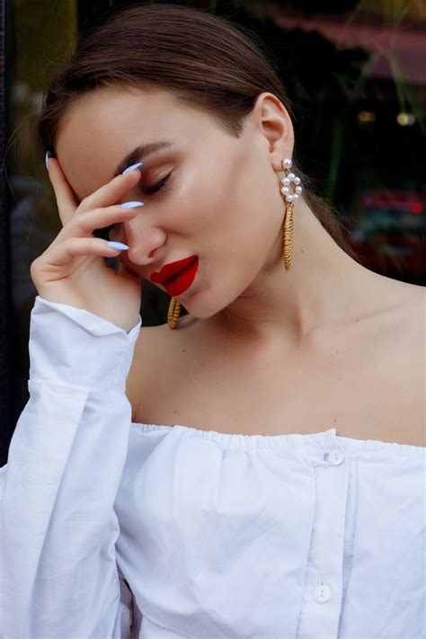 A Woman In A White Shirt Holding Her Hand To Her Face Photo Free