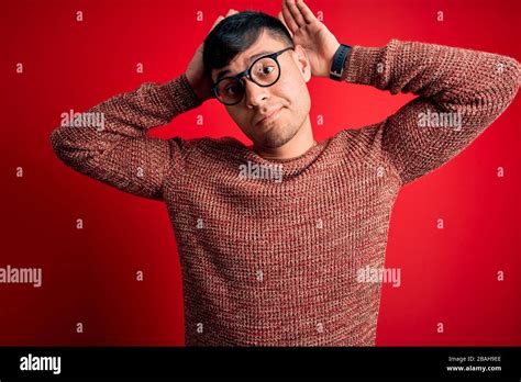 Young Handsome Hispanic Man Wearing Nerd Glasses Over Red Background