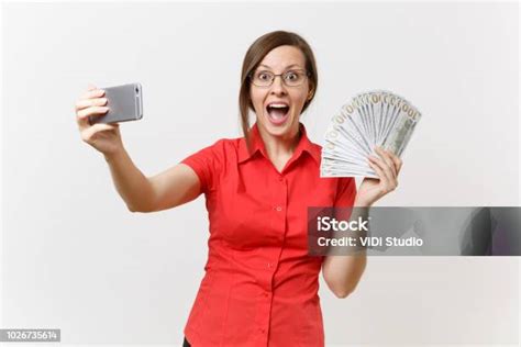 빨간색 셔츠 복용 Selfie 현금 돈 흰색 배경에 고립 된 번들 많은 달러의 휴대 전화에 촬영을 하 고 흥분된 비즈니스 여자