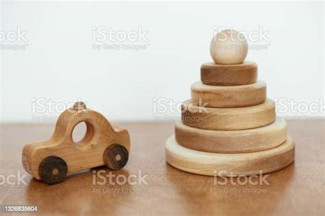 흰색 벽 배경에 나무 테이블에 반지와 자동차 장난감 현대 자연 나무 피라미드 유아를위한 친환경 플라스틱 무료 장난감 아이를위한