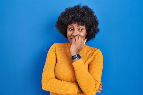 Black Woman With Curly Hair Standing Over Blue Background Looking
