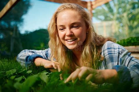 Young Caucasian Woman Smiling While Looking Down At Plants In Plant
