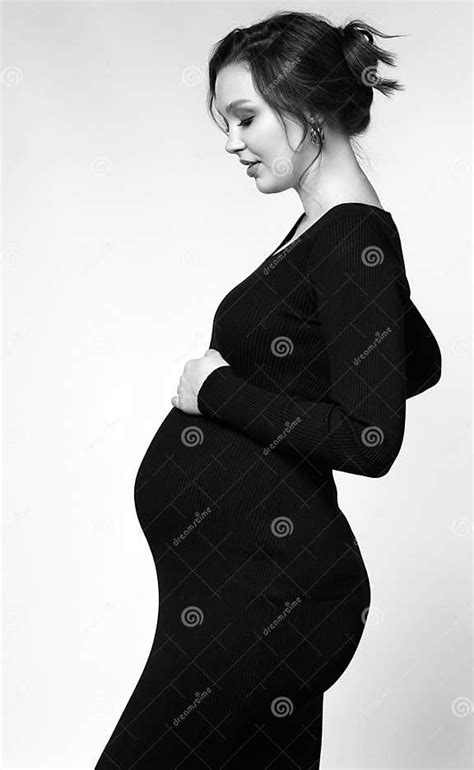 Black And White Portrait Of Pregnant Female In Black Dress With Hands