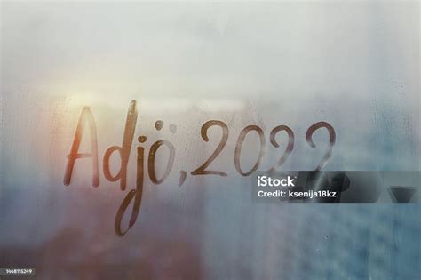 스웨덴어로 된 글자 Adjo는 영어로 작별 인사를 하고 2022년 숫자는 일몰 창에 비에 의해 뿌려진 물에 손가락으로