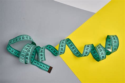 밝은 배경에 녹색 측정 테이프입니다 길이와 부피를 측정하기 위한 도구입니다 의류 산업 또는 인체의 부피를 측정하기 위한 테이프