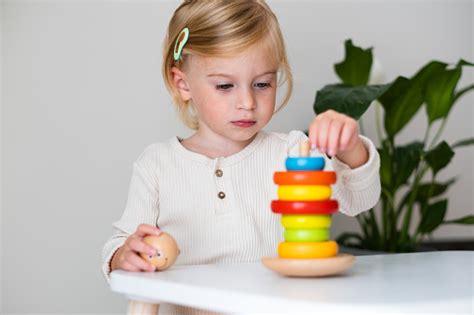 심각한 금발 유아 아이 어린이 흰색 회색 배경에 에코 나무 색 장난감 피라미드와 함께 실내에서 놀고 있는 두 살 소녀 공간을 복사합니다 조기 유치원 개발유치원 게임 12