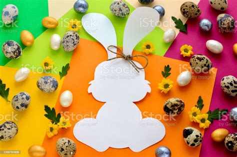 토끼 토끼는 종이 메추라기 계란 잡종 색칠 흰색 사탕과 화려한 기하학적 배경에 누워 작은 노란색 꽃에서 잘라 부활절의 창조적 인 트렌드 개념 공간을 복사합니다 0명에 대한