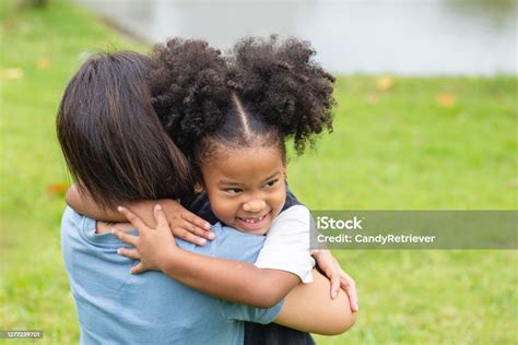 행복한 애정 혼합 인종 가족 귀여운 아이 소녀는 공원에서 이빨 미소와 그녀의 어머니를 포용 엄마와 어린 딸은 여름 야외 주말