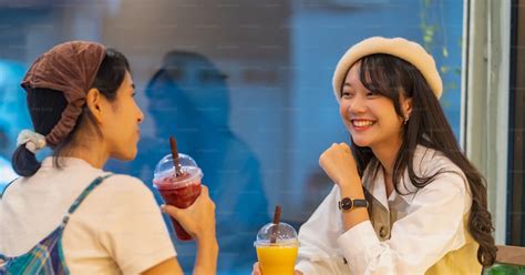젊은 아름다운 아시아 여자 친구들은 카페 창가에 앉아 과일 주스를 마시고 행복과 함께 이야기합니다 매력적인 여성 우정은 도시에서 여가 활동과 만남을 즐깁니다 사진