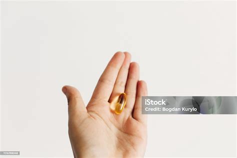 흰색 벽 배경에 오메가 3 캡슐을 손에 들고 있습니다 비타민의 아침 복용량 알약에 생선 기름 식이 보조 제 건강 지원 및 치료