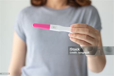 한 젊은 여성의 손이 흰색 바탕에 두 개의 줄무늬가 있는 임신 테스트기를 보여줍니다 긍정적 인 결과 긍정적인 감정 표현에 대한 스톡 사진 및 기타 이미지 Istock