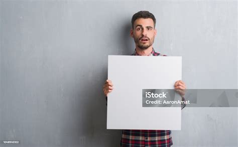 벽돌 벽 잡고 배너 깜짝 얼굴 두려워 하 고 공포 식으로 흥분 충격에서 무서 워 통해 젊은 성인 남자 감정에 대한 스톡 사진 및