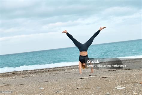 해변에서 즐거운 시간을 보내는 중년의 스포티한 여성이 물 근처에서 사이드 플립을 하고 있다 요가 휴양지 운동 바다에서의 몸과