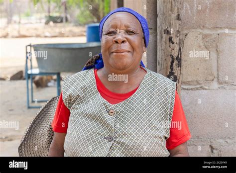 Old African Woman In The Village Sited On A Chair In Her Yard Stock