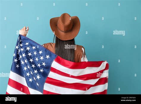 Beautiful Young Cowgirl Holding Usa Flag On Blue Background Back View