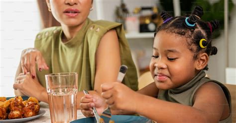 행복한 아프리카 가족 부모와 두 어린 딸이 함께 프라이드 치킨과 피자를 먹고 있습니다 아버지와 어머니와 귀여운 아이 소녀 아이가 집에서 함께 먹고 즐겁게 식사를 나누고