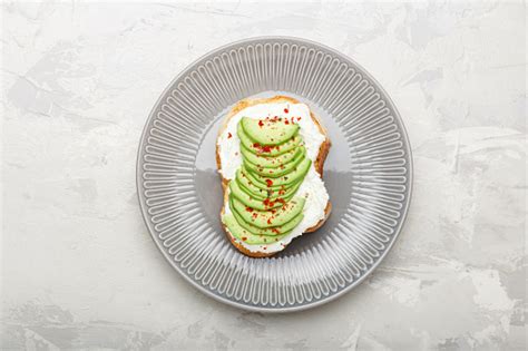 회색 접시에 아보카도 토스트 신선한 아보카도는 밀 빵 크림 치즈의 토스트에 슬라이스 아보카도 샌드위치 칠리 텍스트 상단 보기를