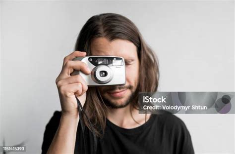 긴 머리와 흰색 배경에 빈티지 구식 필름 카메라를 들고 검은 셔츠에 카메라 뷰파인더를 보고 잘생긴 젊은 수염 남자 검은색에 대한 스톡 사진 및 기타 이미지 Istock