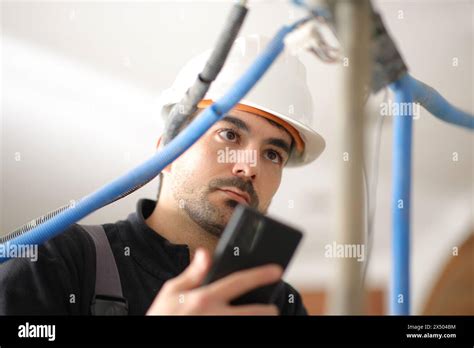 Electrician Checking Installation Using Phone In A House Under