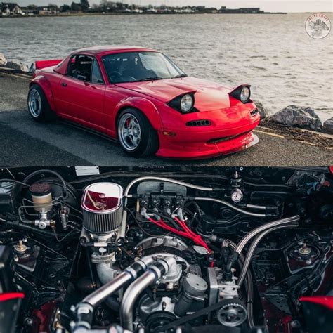 a red sports car parked next to the ocean with its hood up and engine exposed