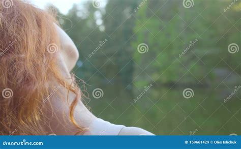 Close Up Of Young Caucasian Woman Stroking Her Long Red Hair And