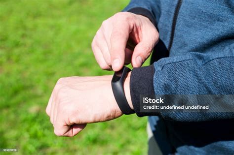 피트 니스 팔찌 또는 남자의 손에 스마트 시계 에 대 한 녹색 잔디의 배경 블루 밴드에 성인 남성입니다 건강 한 라이프 스타일