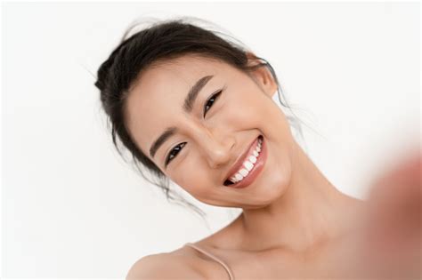 하얀 이빨로 밀링하고 하얀 벽 배경위에 자신의 셀카를 찍는 아름다운 젊은 아시아의 클로즈업 초상화 자연의 아름다움과 건강한 여자