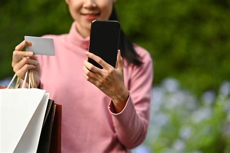스마트폰과 신용 카드로 온라인으로 결제하는 쇼핑백을 들고 있는 스미진 여성의 잘린 사진 25 29세에 대한 스톡 사진 및 기타