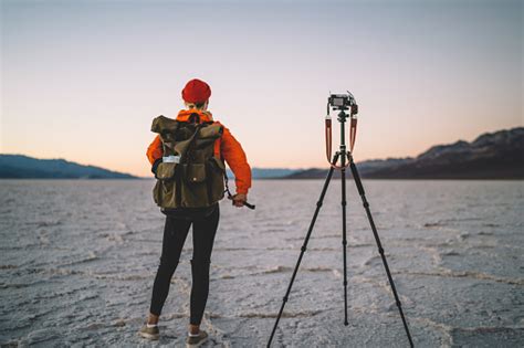 풍경과 야생 자연의 사진을 만들기위한 현대적인 장비를 사용하여 관광 배낭과 여성의 백보기 사막 탐험에서 작업하는 동안 삼각대를 사용하여 전문 여성 사진 작가 건조 기후에