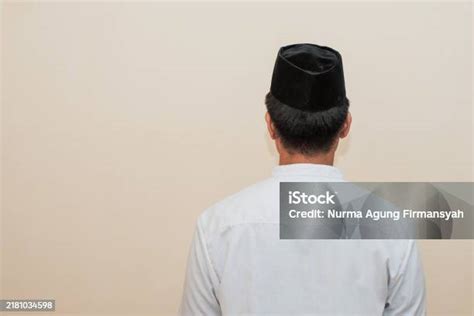 머리 모자를 쓴 흰색 무슬림 옷을 입고 흰색 배경 위에 서 있는 동남아시아 무슬림 남자의 뒷모습 Eid Mubarak에 대한 스톡 사진 및 기타 이미지 Istock