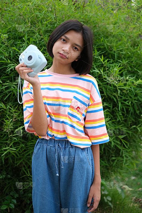 快乐的年轻亚洲女孩与蓝色相机和自然背景。