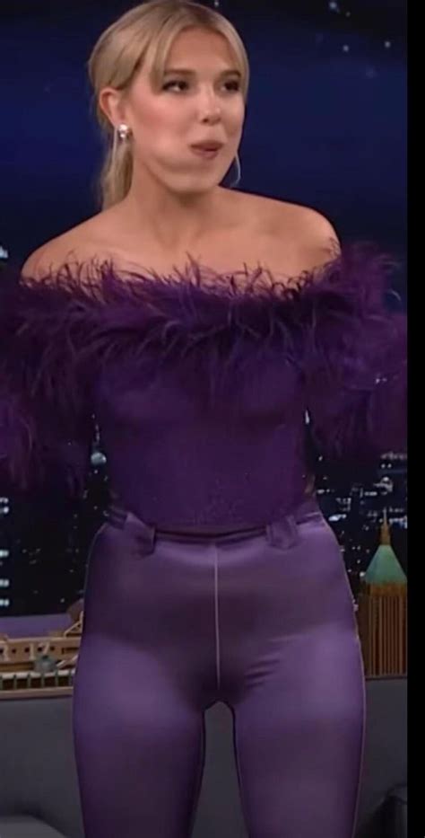 A Woman Wearing Purple Pants And An Off The Shoulder Top Is