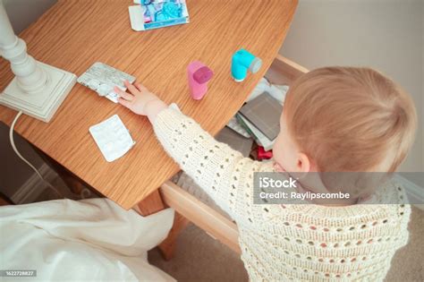 처방약으로 가득 찬 침대 옆 캐비닛을 들여다보는 유아는 어린이의 손이 닿는 곳에 알약을 보관하는 것의 위험성을 강조합니다 2 3