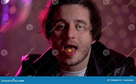 Guy Holding Narcotic Pill On Tongue In Night Club Unhealthy