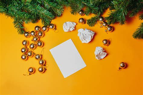 복사 공간이있는 크리스마스 카드 크리스마스 장식품 플랫 오렌지 배경에 누워 여자는 주위에 종이의 구겨진 조각으로 흰색 시트에 크리스마스 소원을 씁니다 0명에 대한 스톡 사진