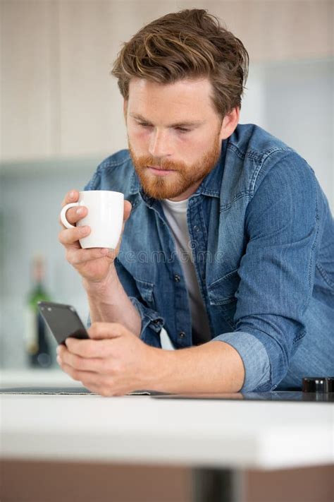 Handsome Young Man Holding Mobile Phone And Drinking Coffee Stock Image