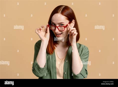 Surprised Woman With Red Hair Is Adjusting Her Red Glasses With A