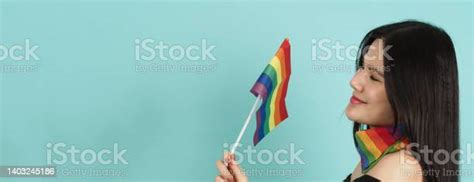 Lgbtq 여성이 푸른 녹색 배경에 서있는 자존심 깃발을 들고 있습니다 목에 무지개 스카프를 가진 아시아 Lgbtq 여성