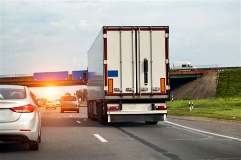 세미 트레일러가 달린 트럭이 일몰과 자동차 통행을 배경으로 고속도로를 따라 달리고 있습니다 트럭용 유료 도로의 개념 킬로미터당 가격 텍스트 산업을 위한 복사 공간 0명에