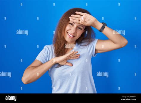 Brunette Woman Standing Over Blue Background Smiling Cheerful Playing Peek A Boo With Hands