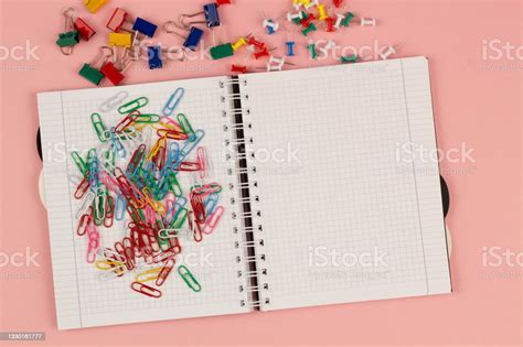 분홍색 배경에 학교 제곱 노트북과 다채로운 클립을 엽니 다 테이블에 종이 책의 빈 흰색 시트 바탕 화면에 사무실 공급 학교로