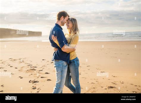 Happy Man And Woman Embracing Each Other In Front Of Sea At Beach Stock