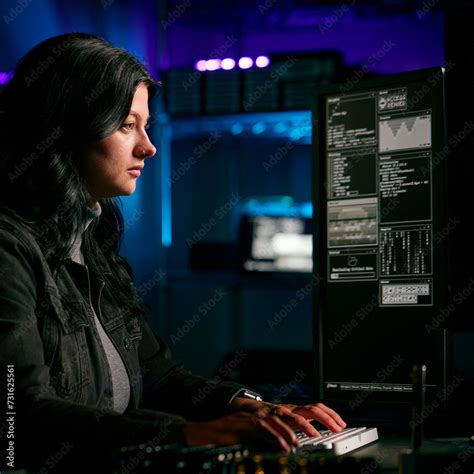 Low Key Lighting Shot Of Female Computer Hacker Sitting In Front Of Screens Breaching Cyber